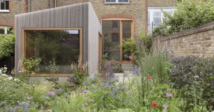 This Home Extension Covered In Vertical Wood Slats Includes A Picture ...